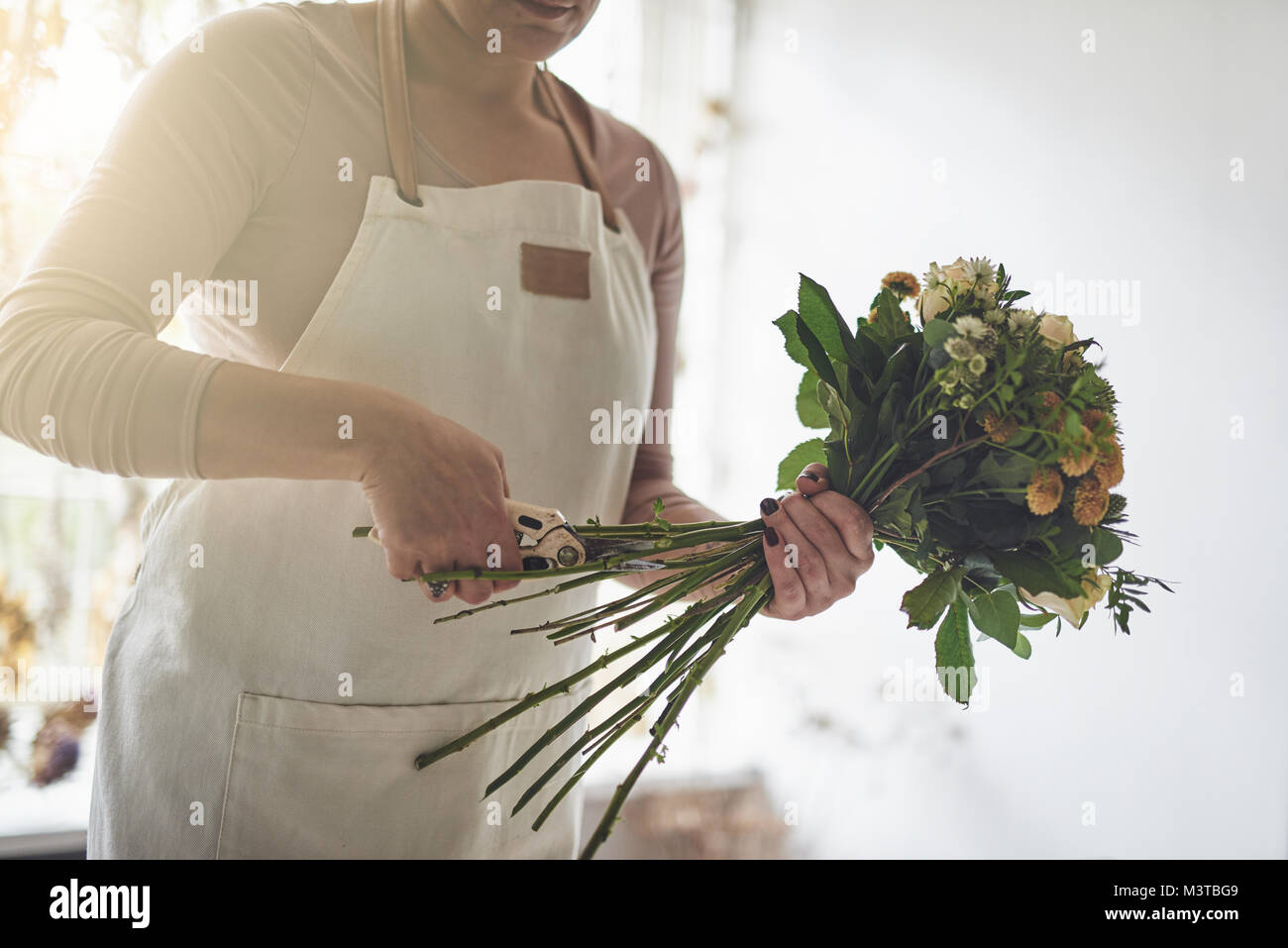 Young female florist trimming flower stems in shop hi-res stock ...