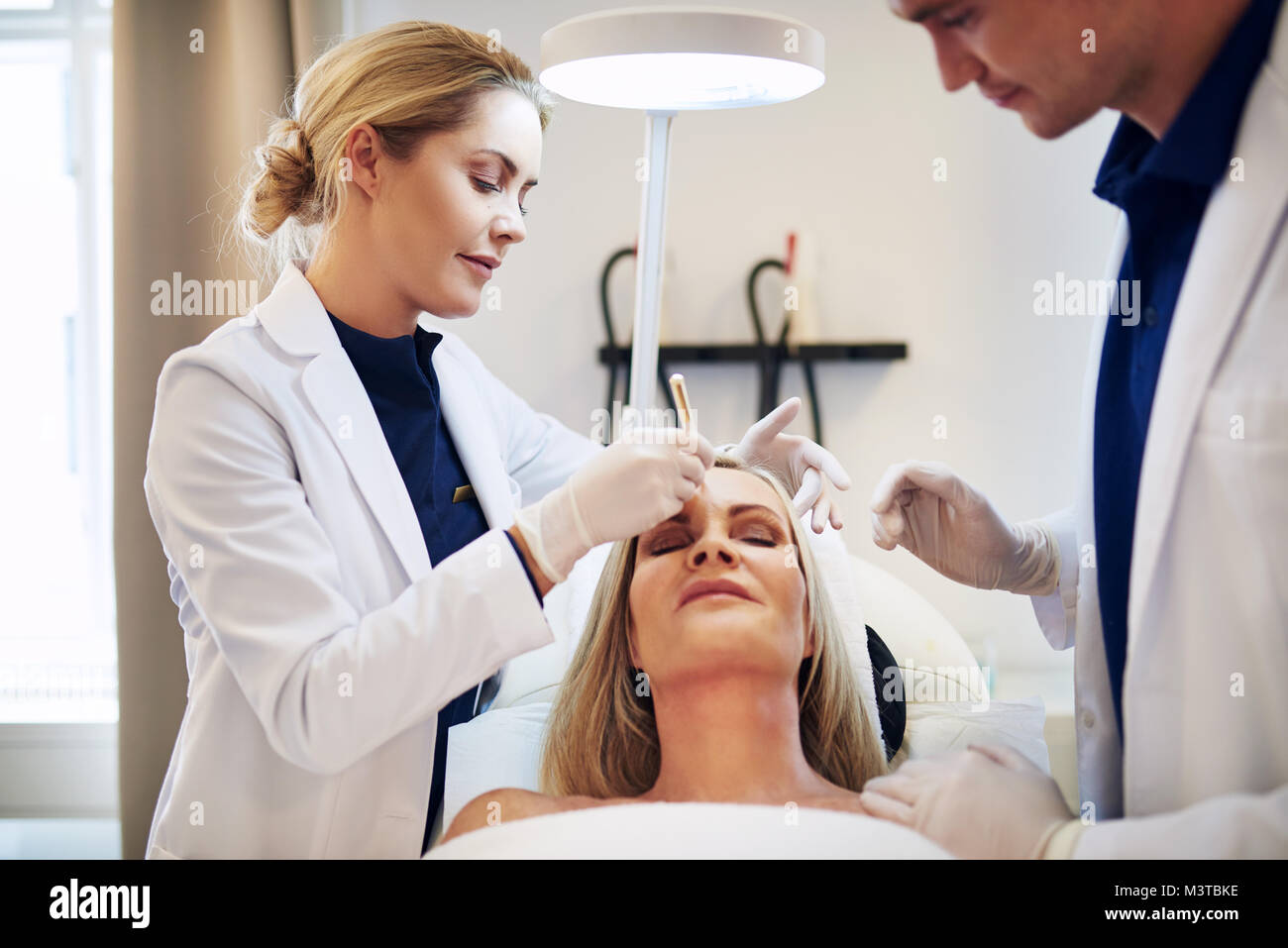 Two young doctors discussing a cosmetic surgery procedure on the face ...