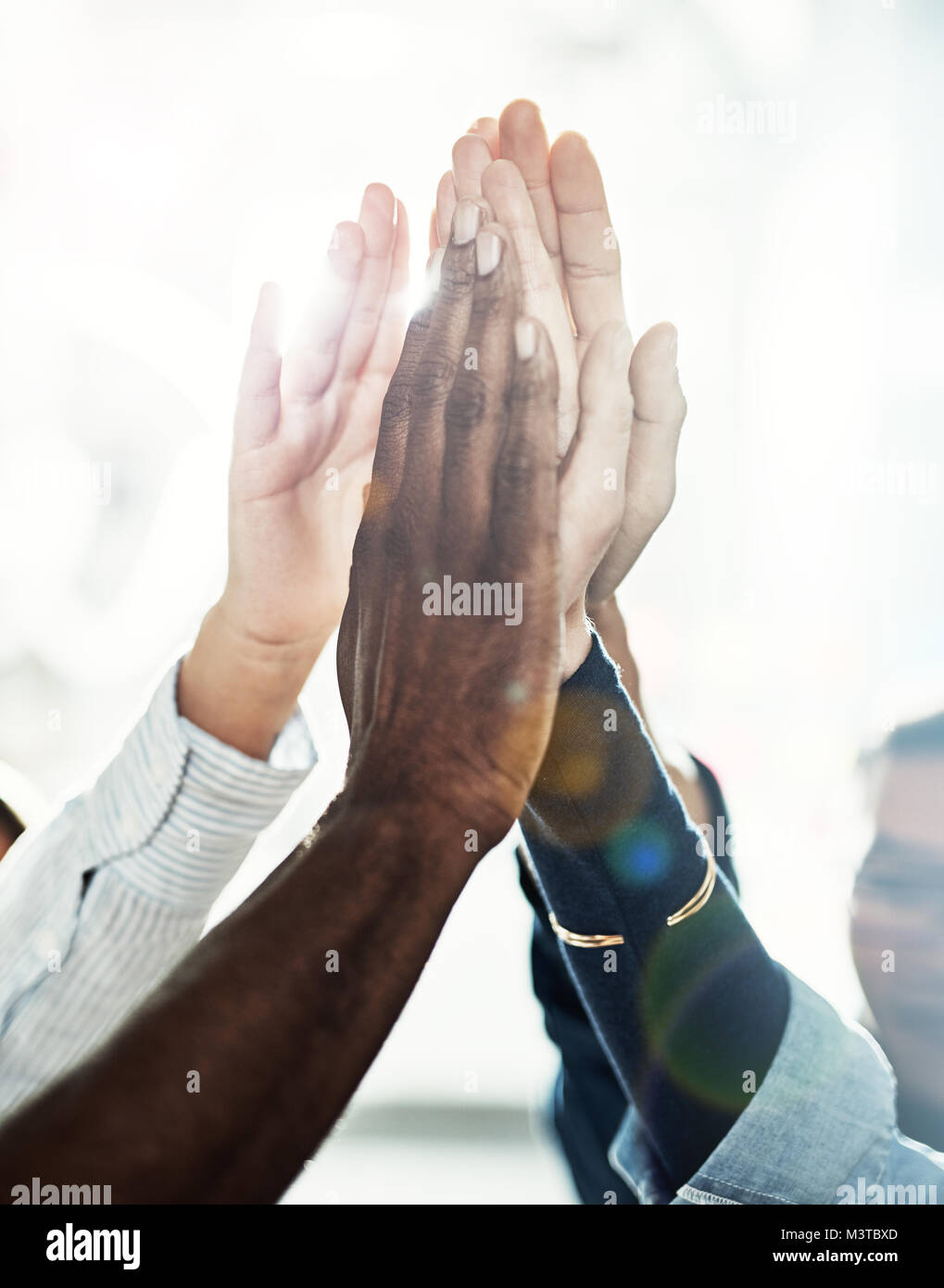 Group of diverse businesspeople high fiving each other while standing ...