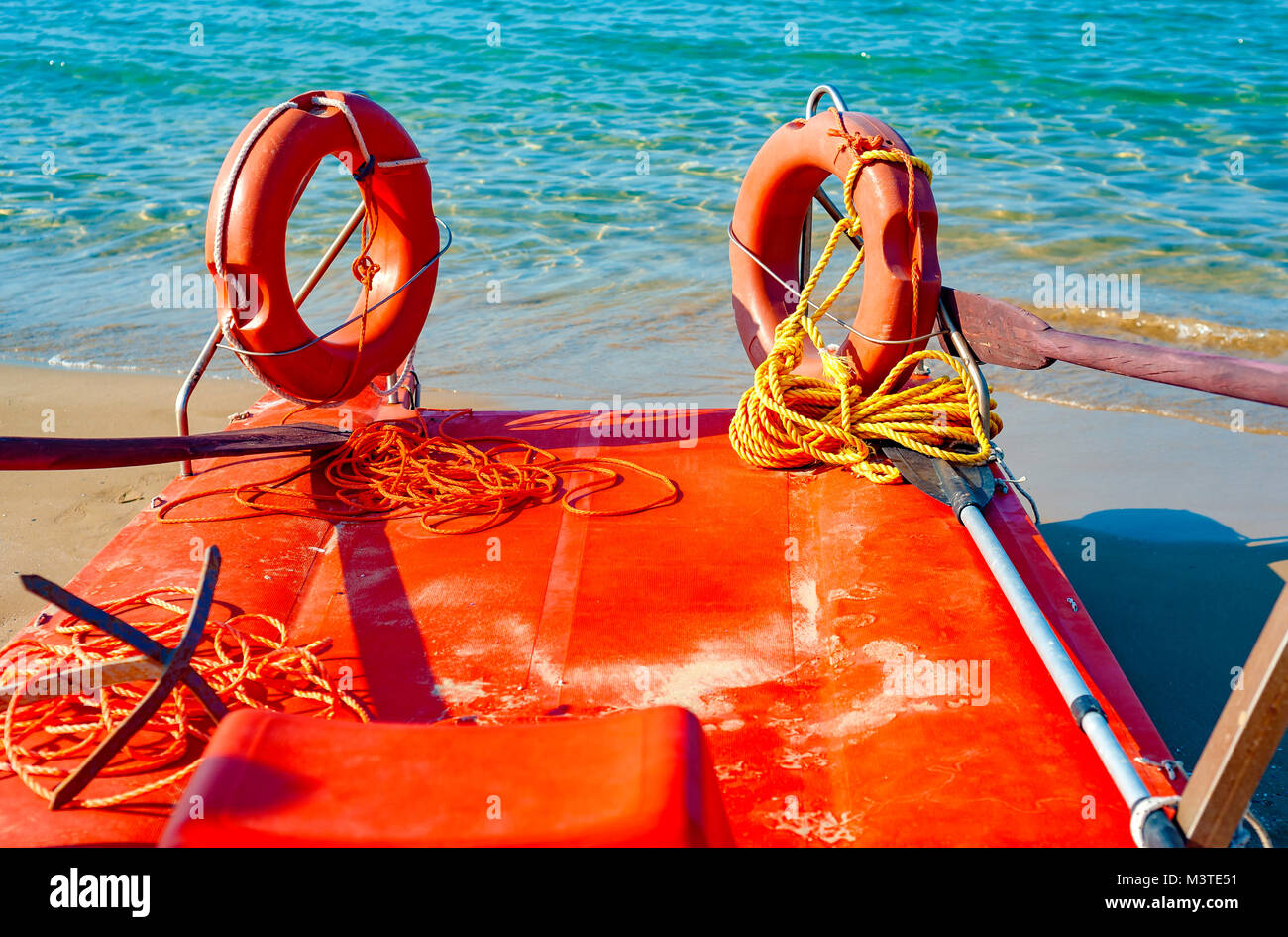 Close up lifeboat on the beach. The sea is calm and the bathers are at ...
