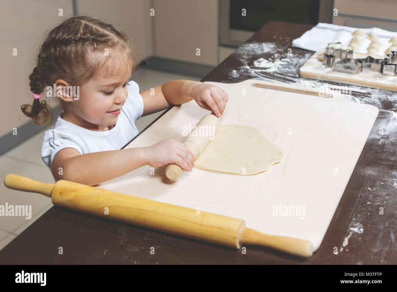 Little girl rolls out the dough with a small rolling pin Stock Photo ...