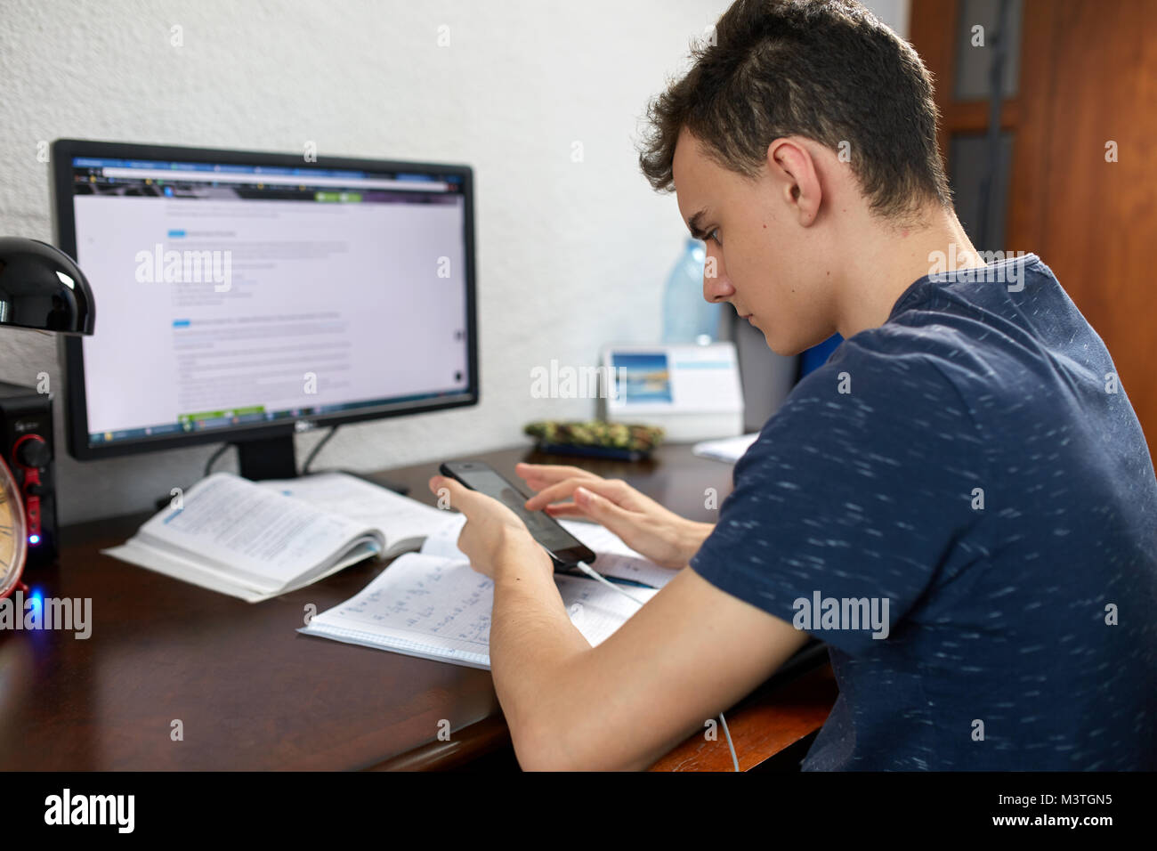 Student doing homework at his desk with computer Stock Photo - Alamy