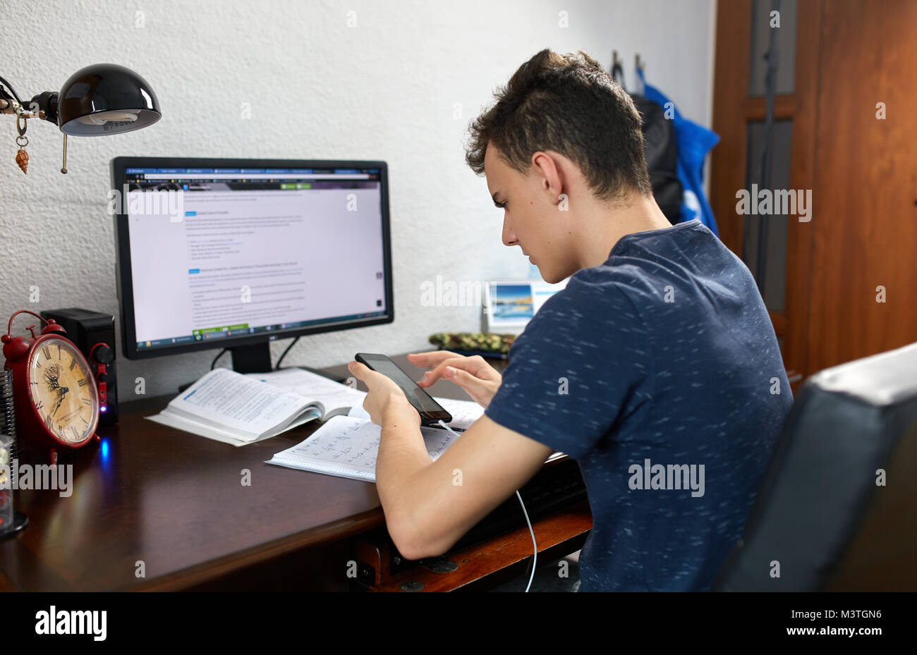 Student doing homework at his desk with computer Stock Photo - Alamy