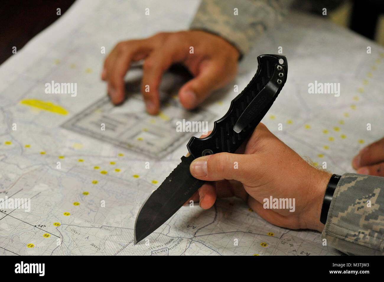 Staff Sgt. Jason Robertson uses a knife to point at an area on a map ...