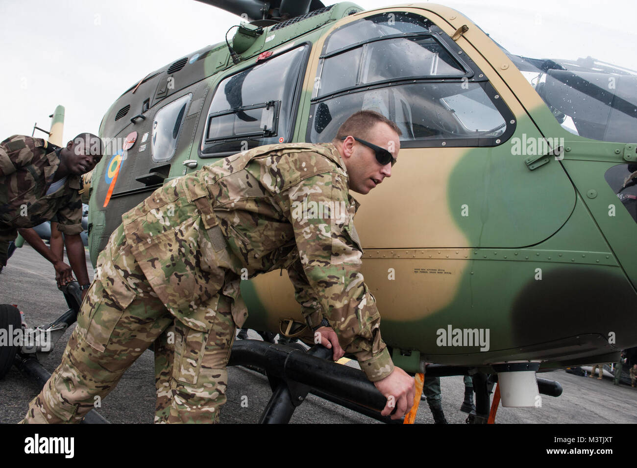 U.S. Army MAJ. Jeffrey Sills, an aeromedical evacuation officer, assist ...