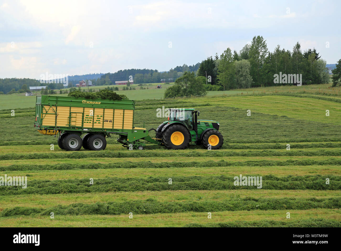 FORSSA, FINLAND – JULY 20, 2014: John Deere 6210R tractor and Krone MX ...