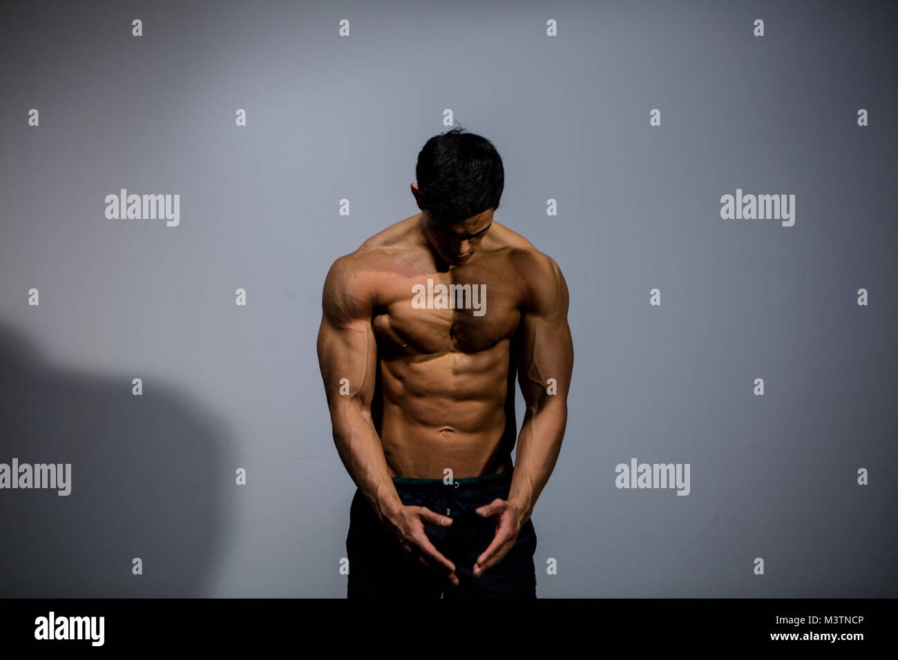 A male fitness model gathering his hands together and flexing pectoral ...