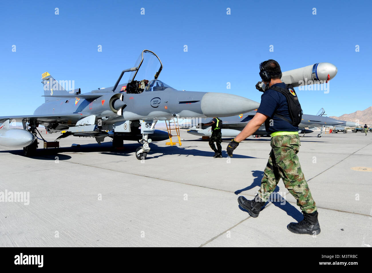 A Colombian air force maintainer carries a drag chute canister for an F ...