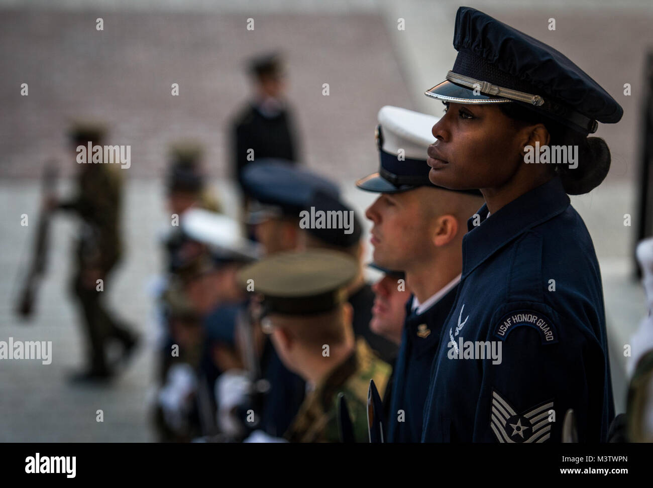 A joint service honor guard cordon stand at ease during a break in ...