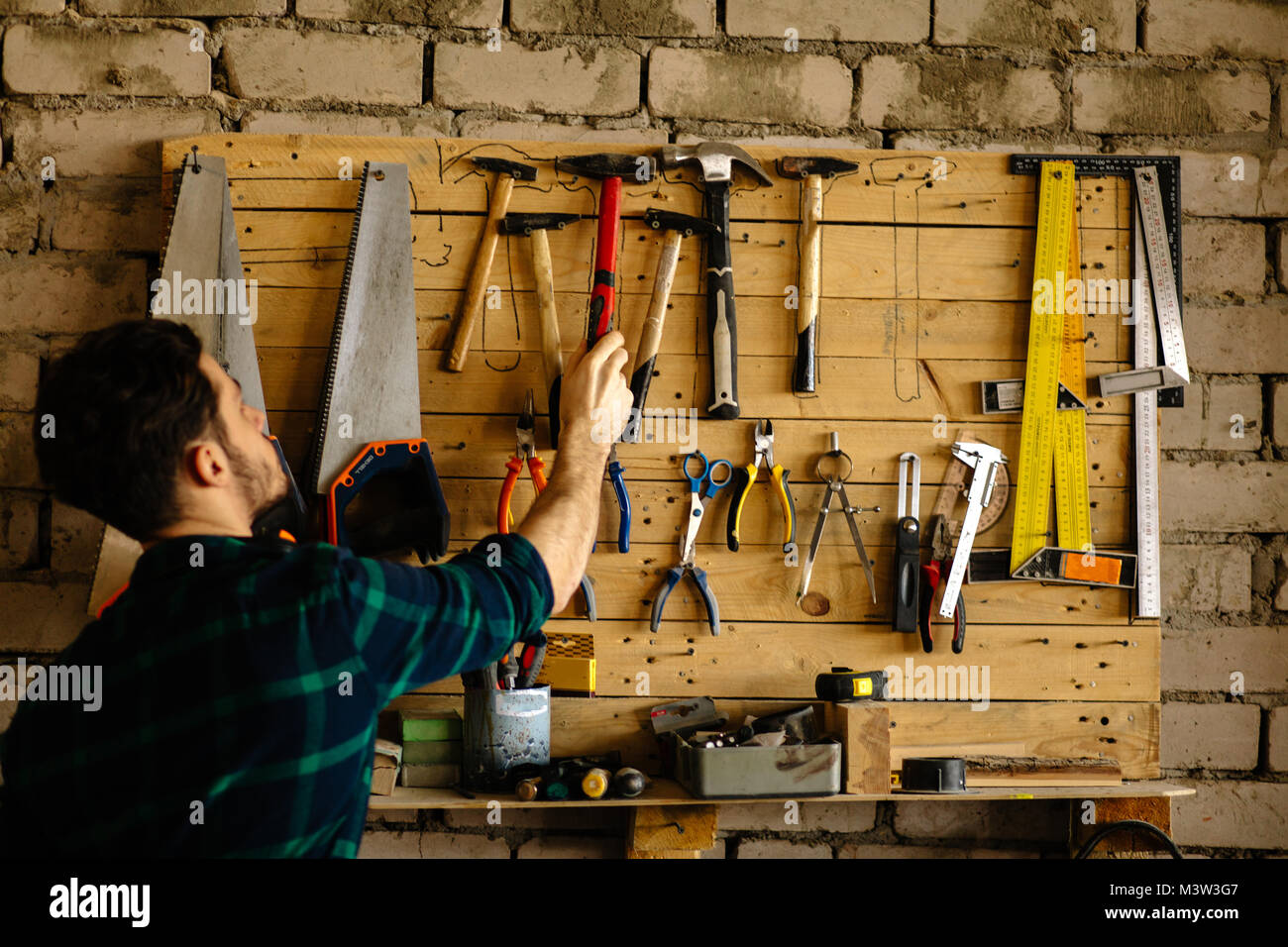 man takes hammer from wall with tools Stock Photo - Alamy