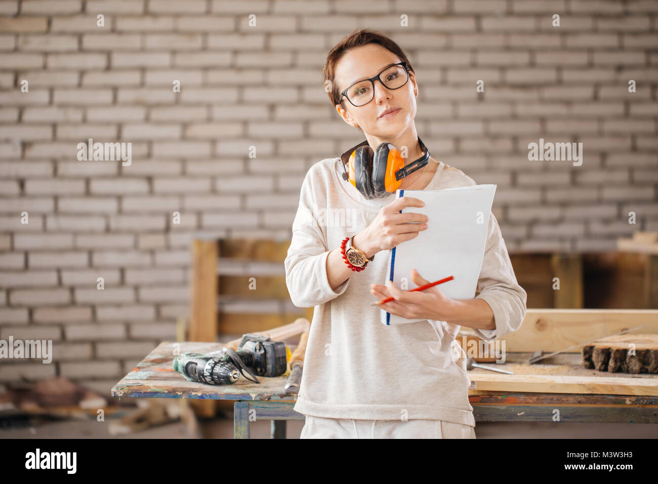 hardworking professional female worker with pen and tablet in workshop ...