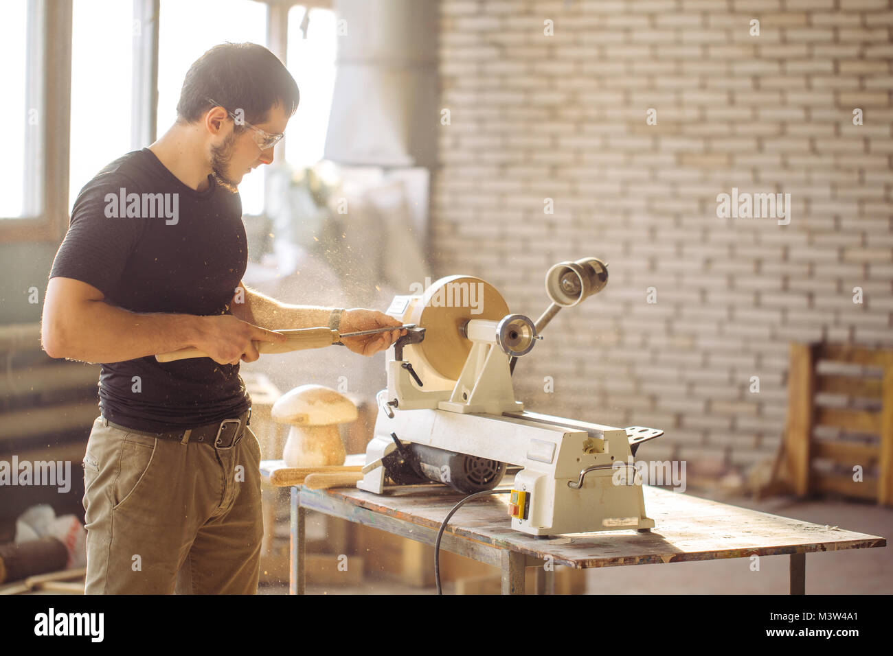 man working at small wood lathe, an artisan carves piece of wood Stock ...