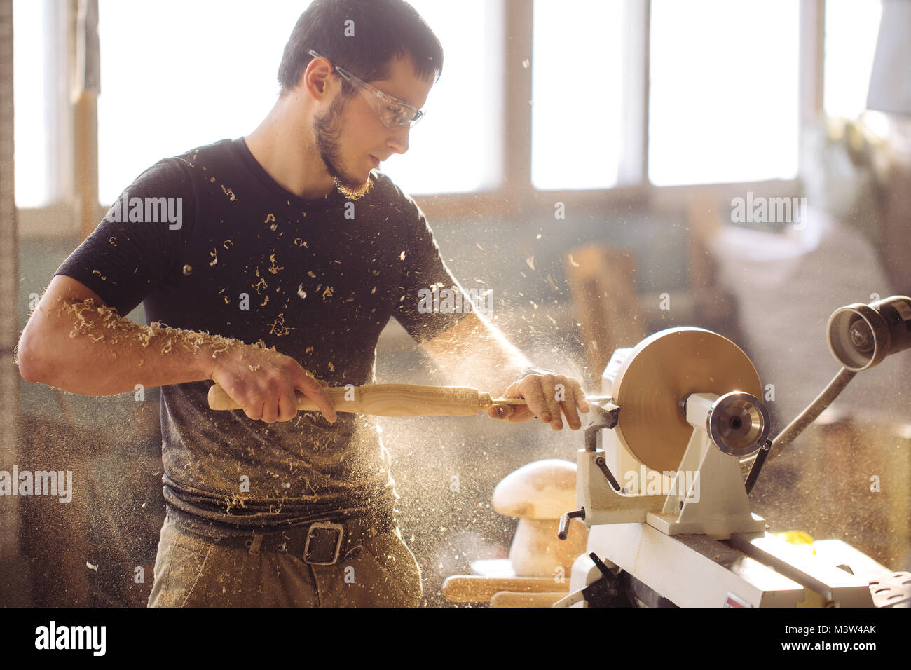 man working at small wood lathe, an artisan carves piece of wood Stock ...