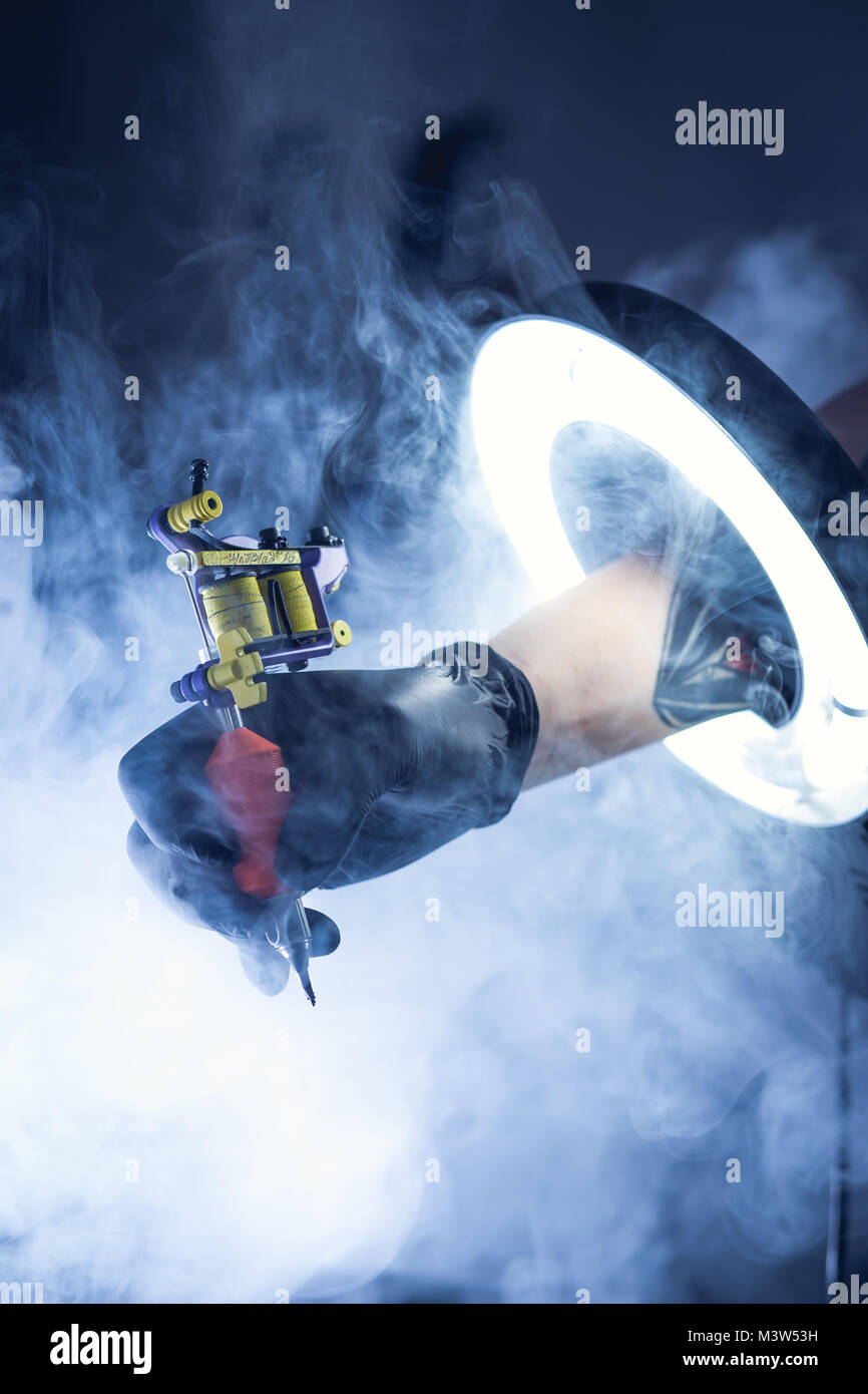 Tattoo artist holding tattoo machine Stock Photo - Alamy