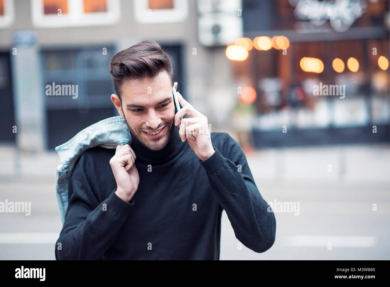 Young handsome man using his cell phone, enjoying a day on the street ...