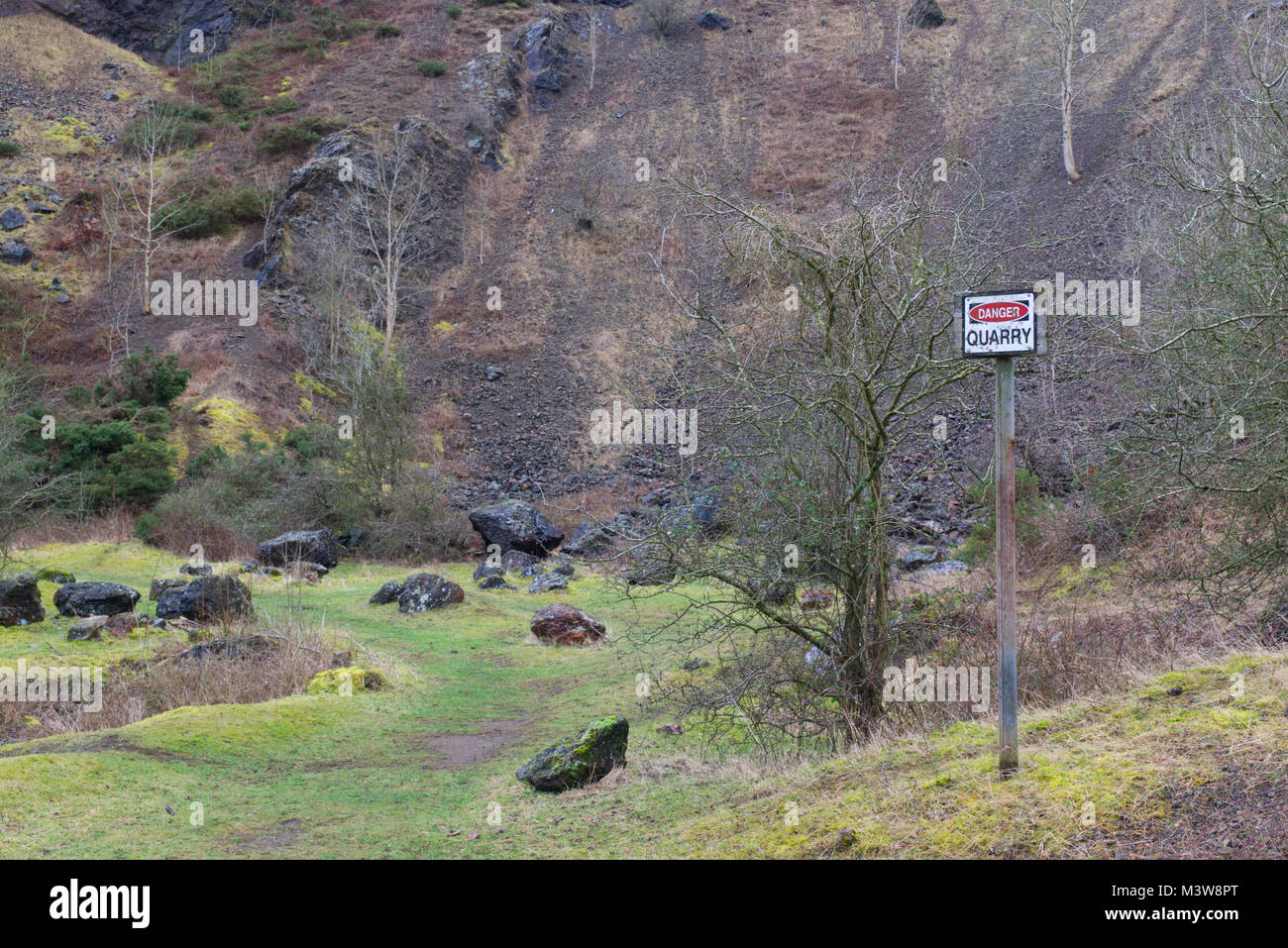 Old closed down quarry with old weathered danger sign and trees taking ...