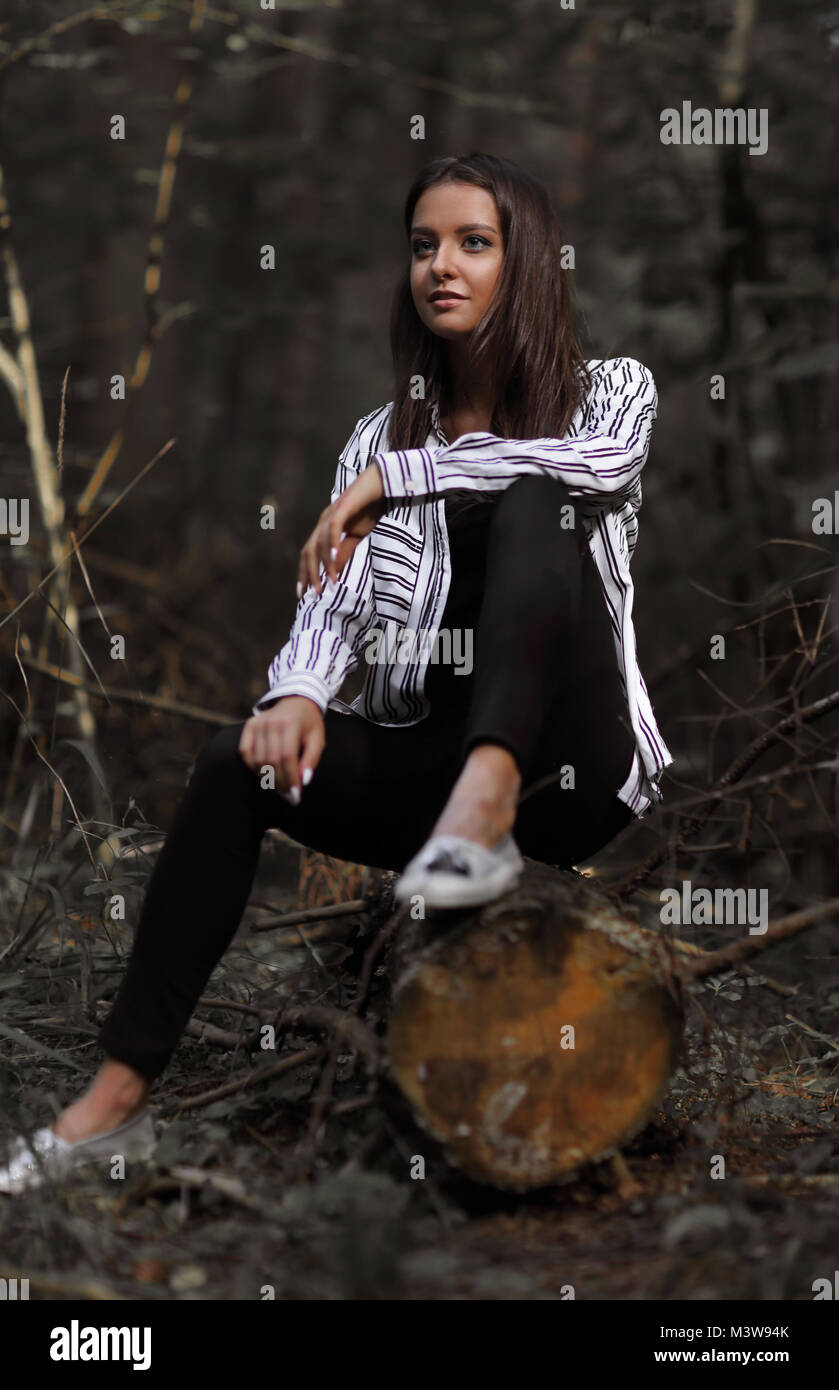 beautiful young woman sitting on a log Stock Photo - Alamy