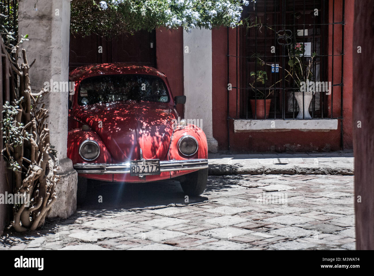 A red Volkswagen Beetle parked in the courtyard of a traditional ...
