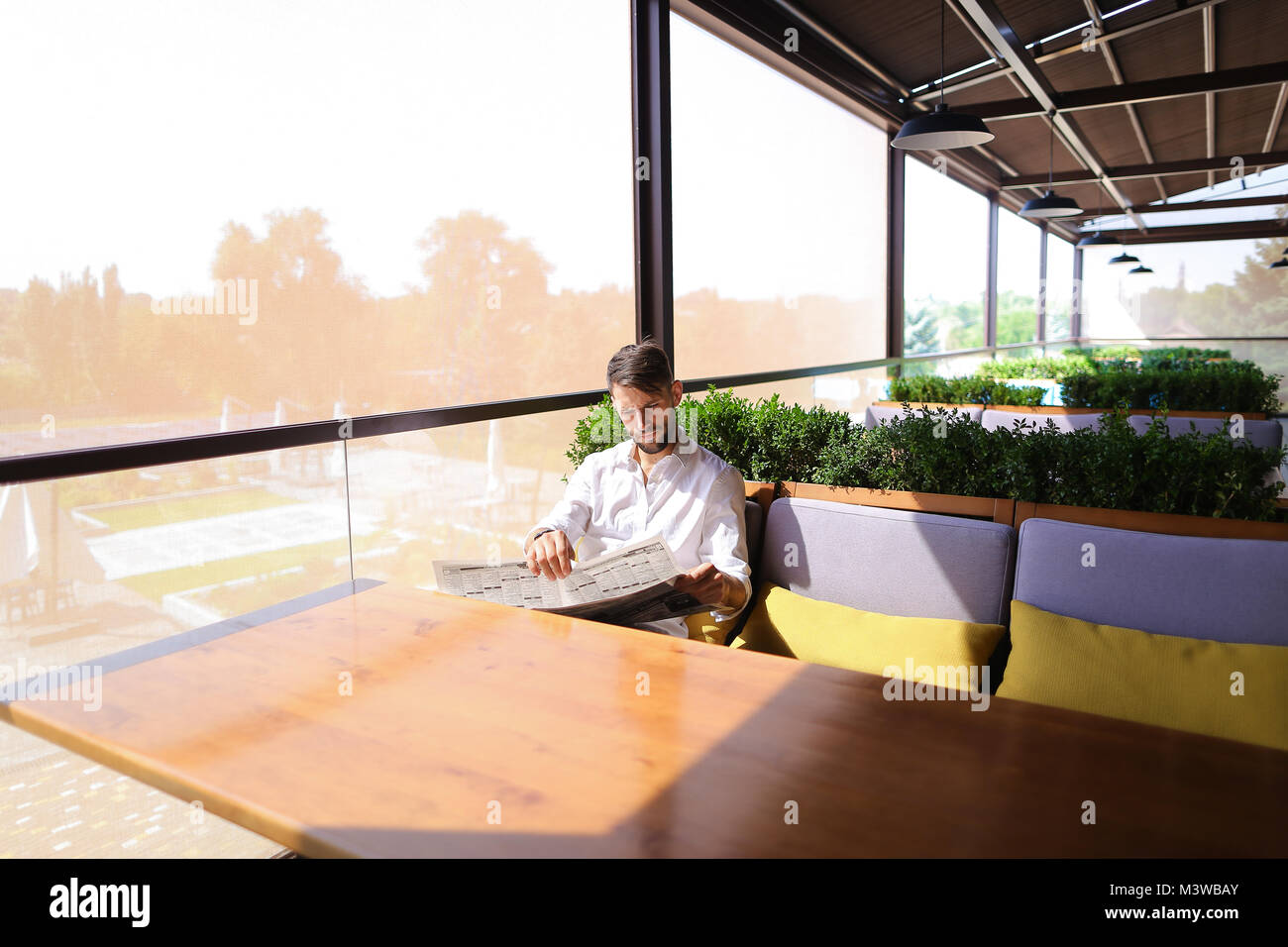 Prosperous man reading newspaper articles and resting Stock Photo - Alamy