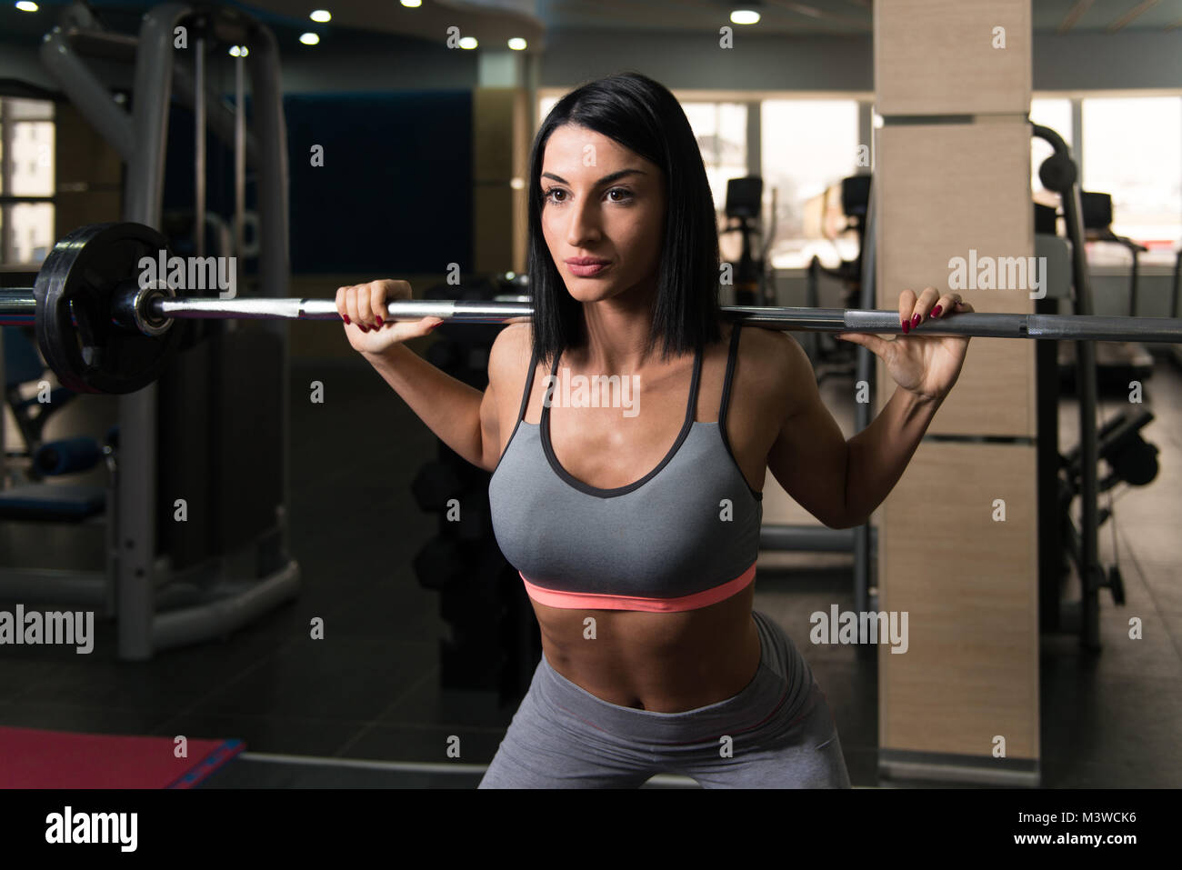 Healthy Fitness Woman Working Out Legs With Barbell In A Gym - Squat ...
