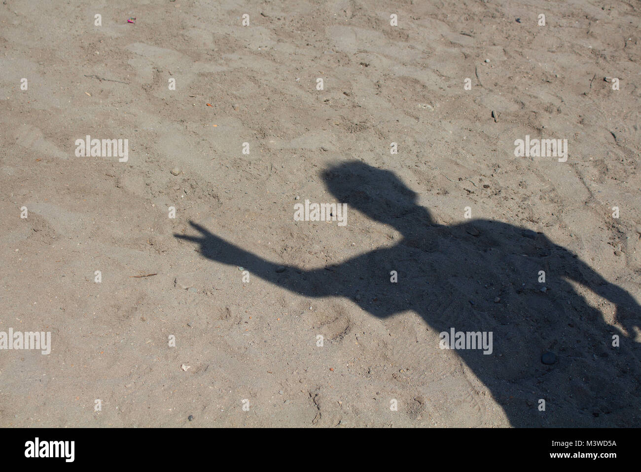 Shadow of man doing peace/victory sign on sand background Stock Photo ...
