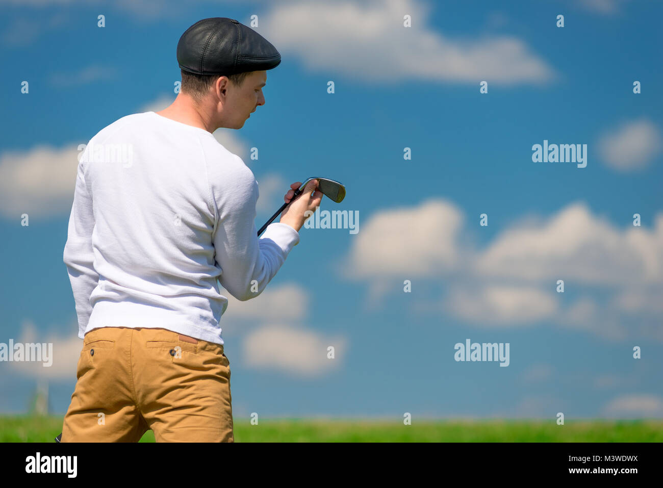 golfer checks his golf club before hitting the ball on the field Stock ...