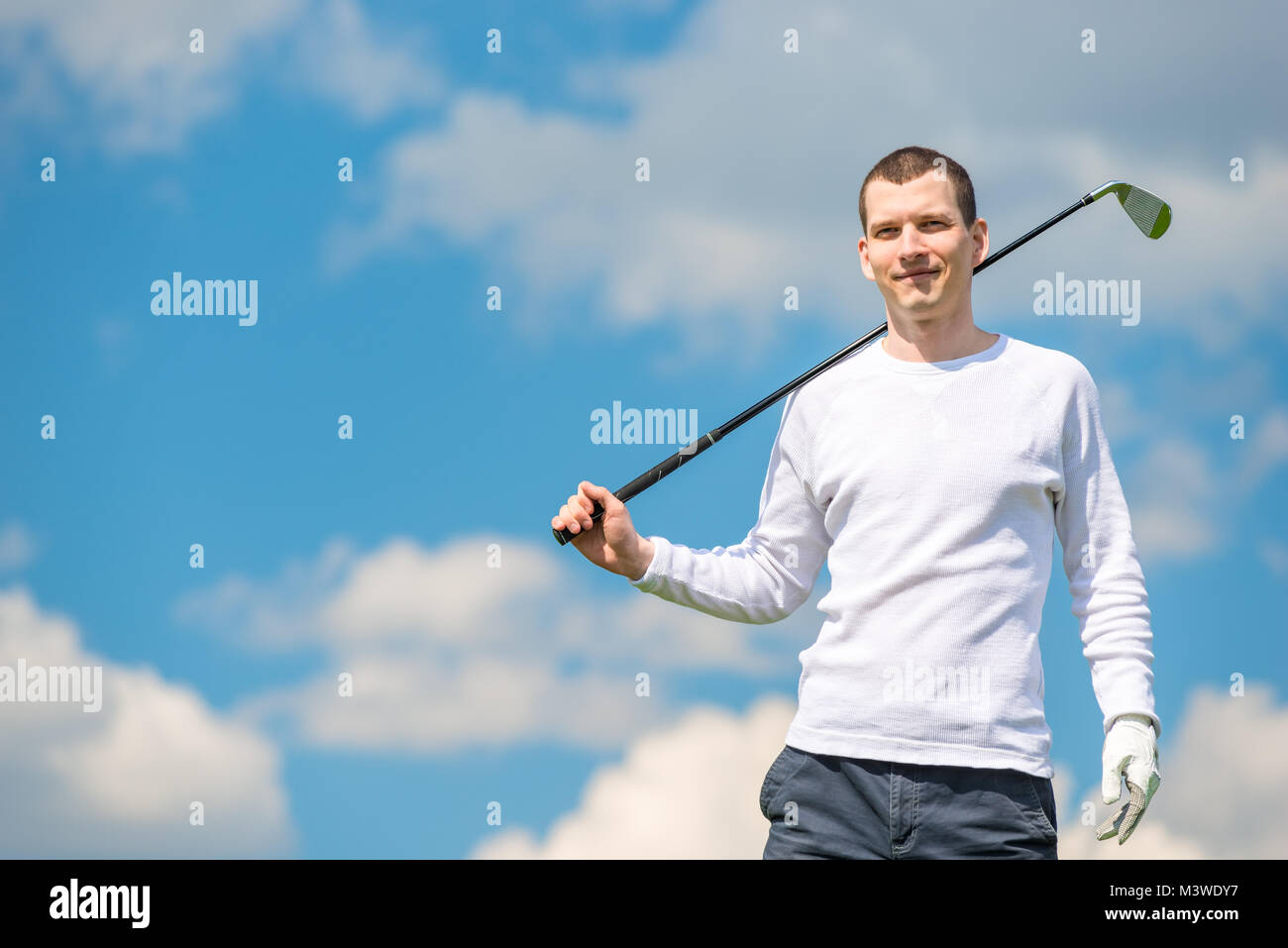 horizontal portrait of a successful golfer with a golf club on a blue ...