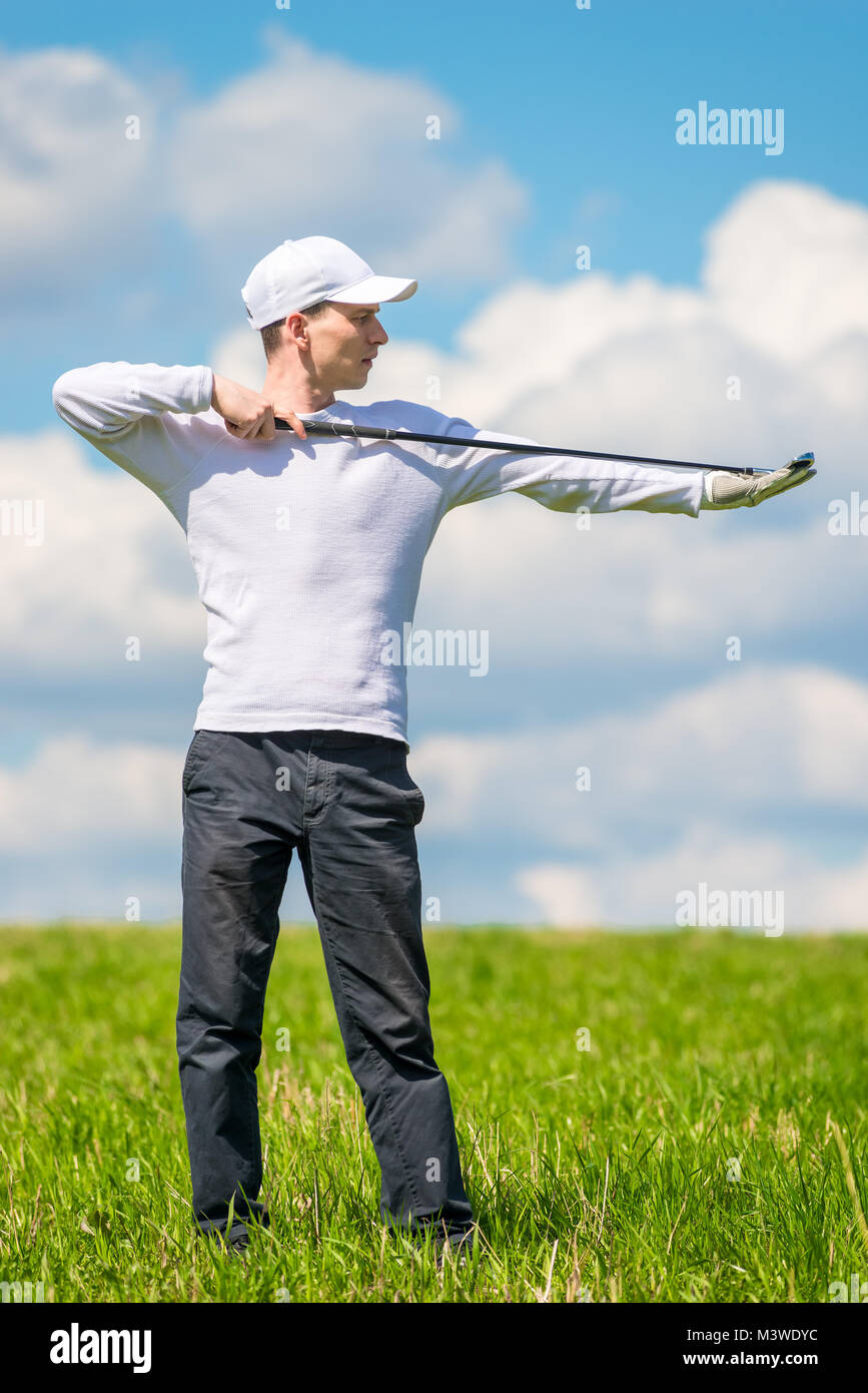 male professional golfer posing with a golf club in a green field on a ...