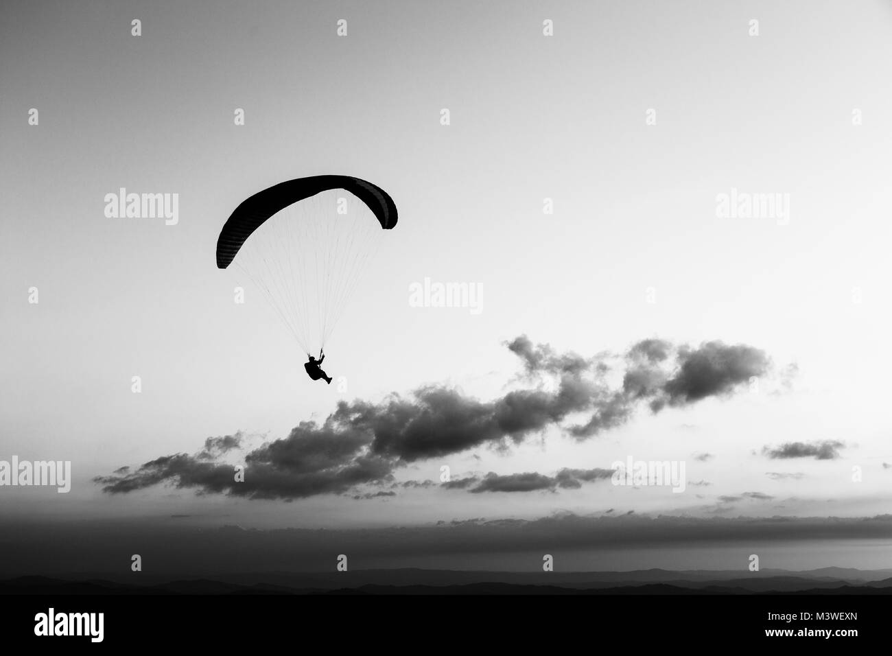 Beautiful shot of a paraglider silhouette flying over Monte Cucco ...