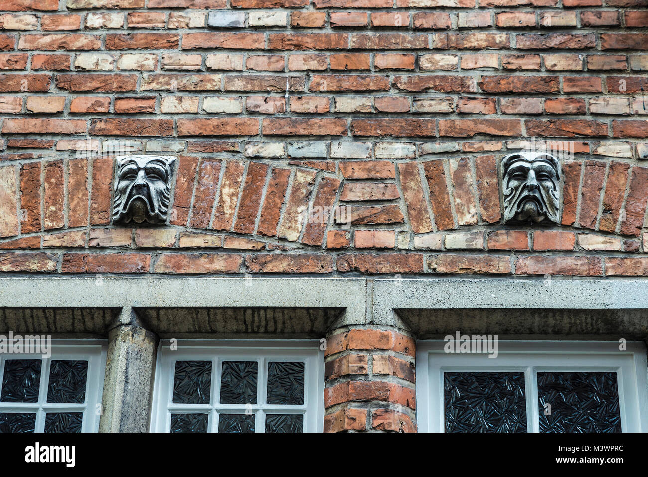 Facade of old historic building with sculptures of angry faces in the ...