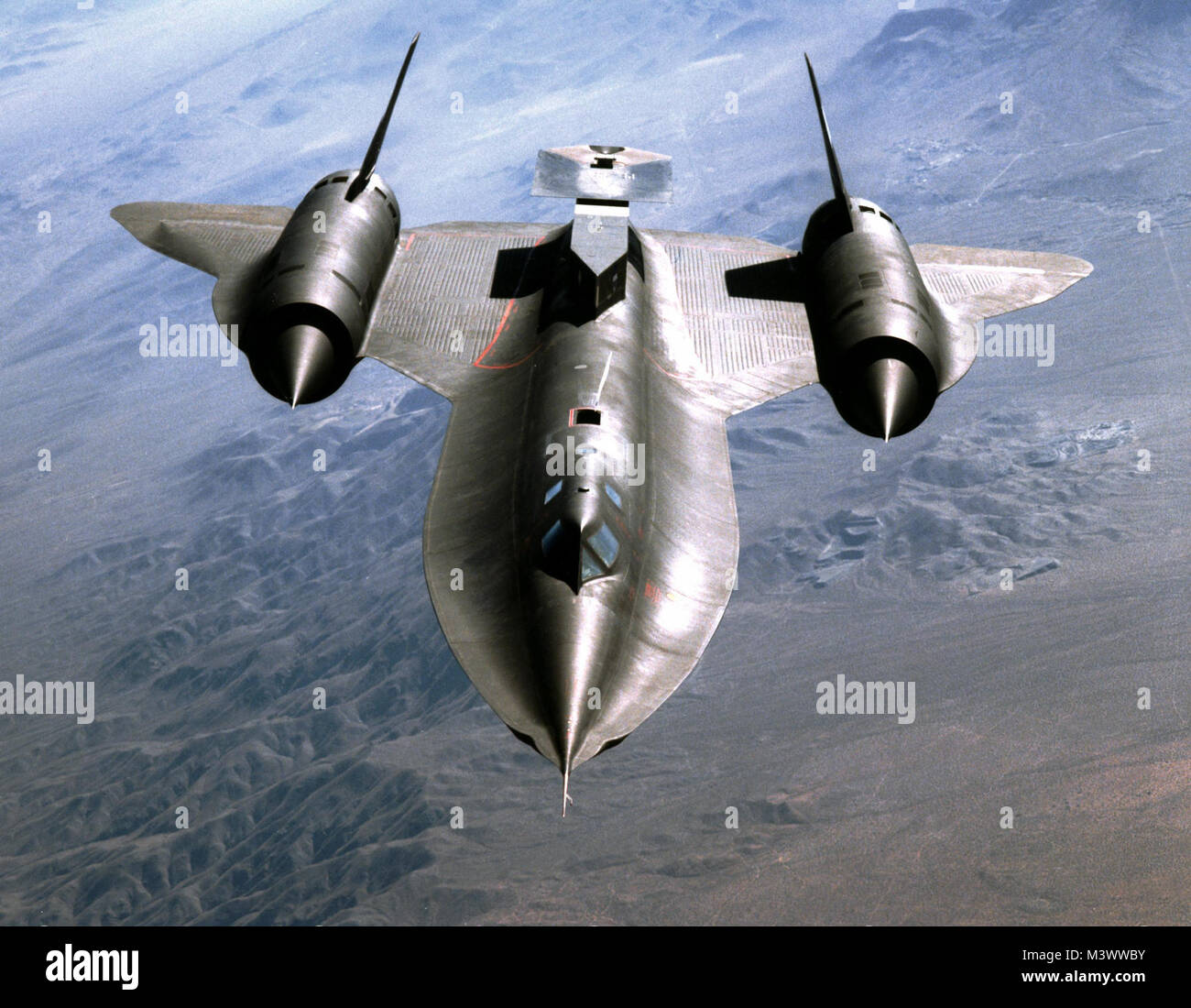An SR-71 is shown in flight with an experimental test fixture mounted ...