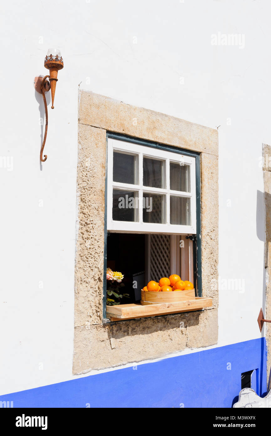 An arrangement of oranges in a small basket on the ledge of a window ...