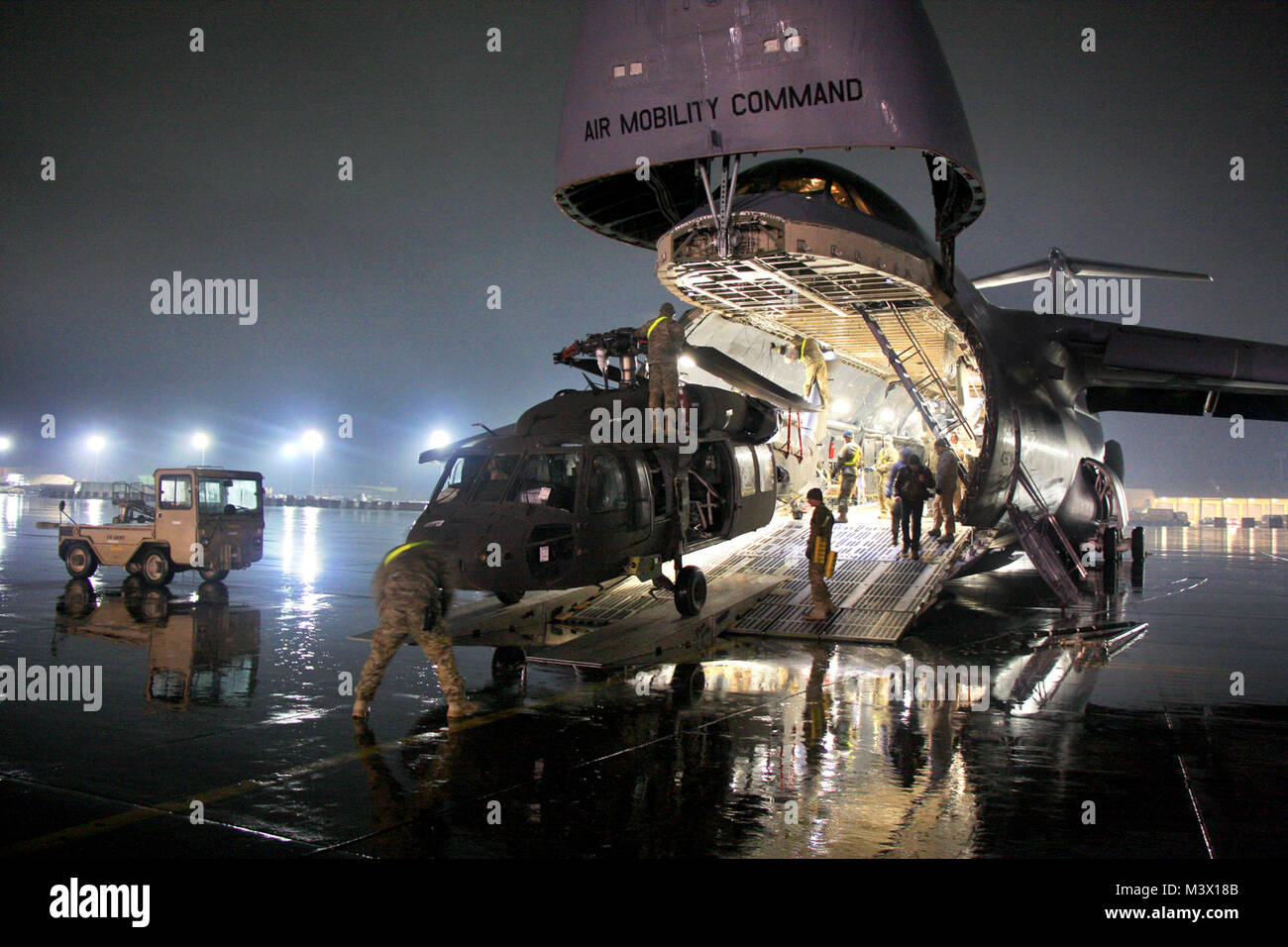 Soldiers and airmen offload A UH64 Black Hawk helicopter from a ...