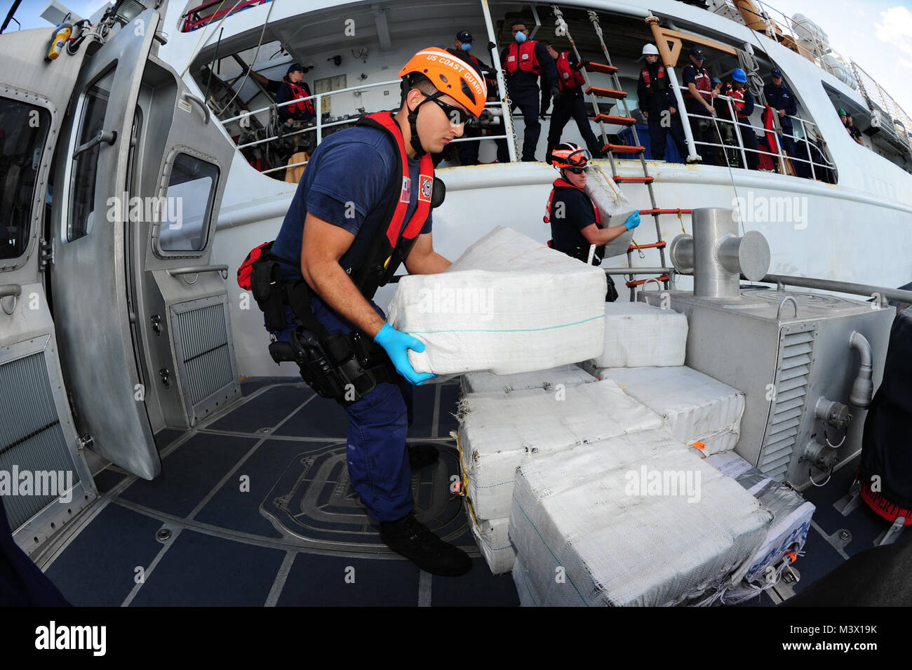 Crew members aboard the Coast Guard cutter Valiant transfer bales of ...