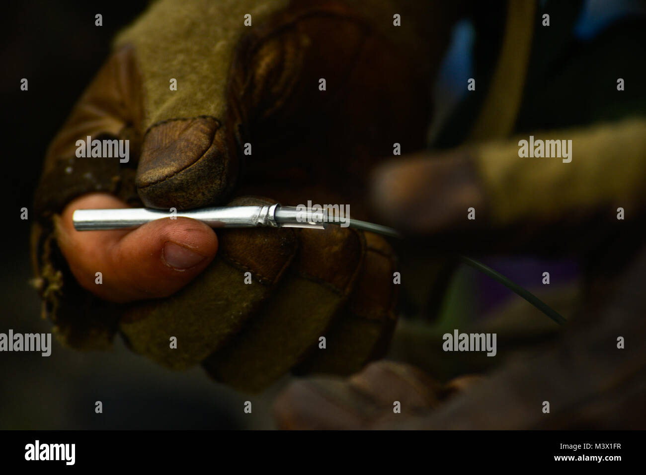 An explosive ordnance technician attaches a blasting cap (inert) to a ...