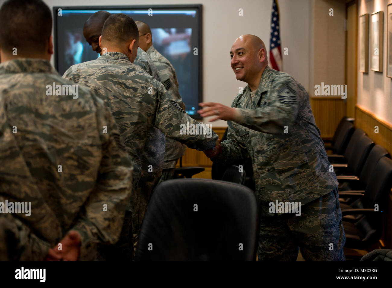 Chief Master Sgt. Jose Barraza walks around a table shaking the hands ...