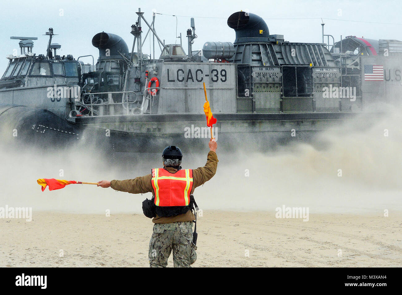 A sailor guides a U.S. Navy LCAC (Landing Craft Air Cushioned) off a ...