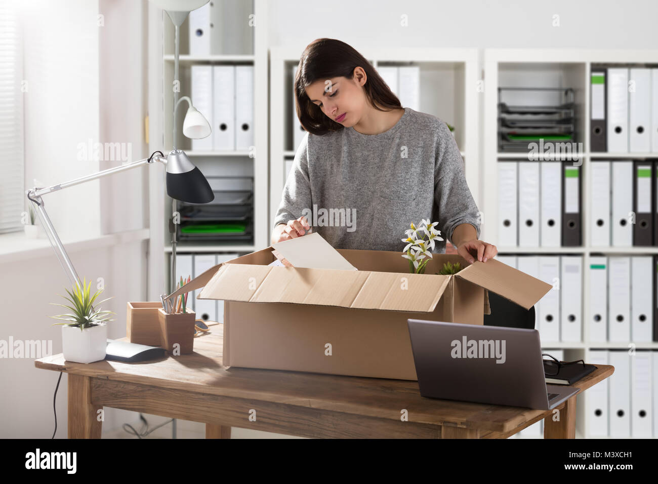 Sad Young Businesswoman Packing Her Belongings In Cardboard Box At ...