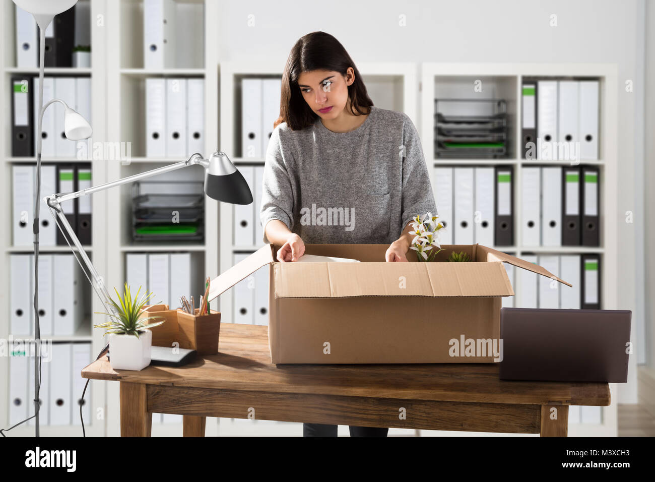Sad Young Businesswoman Packing Her Belongings In Cardboard Box At ...