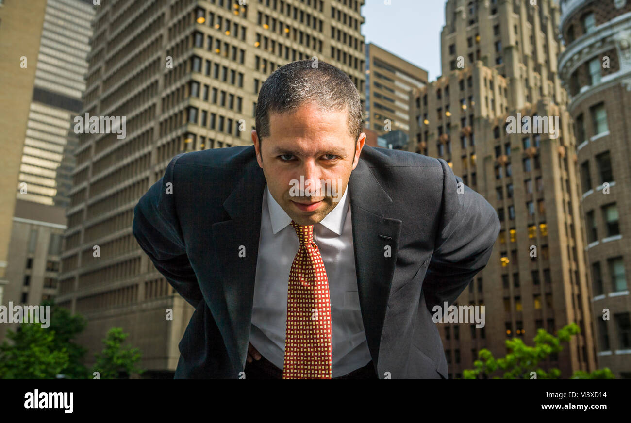 Portrait of a businessman leaning over looking directly into camera in ...
