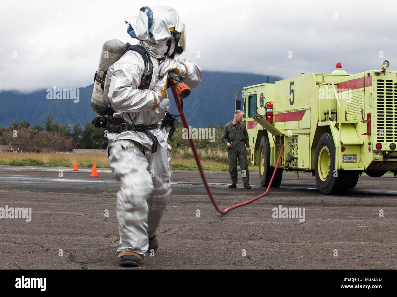 A U.S. Marine with Aircraft Rescue Fire Fighting (ARFF) unrolls a ...