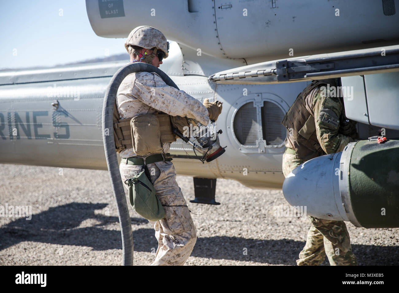 A Marine with Marine Wing Support Squadron 371 carries a jet fuel line ...