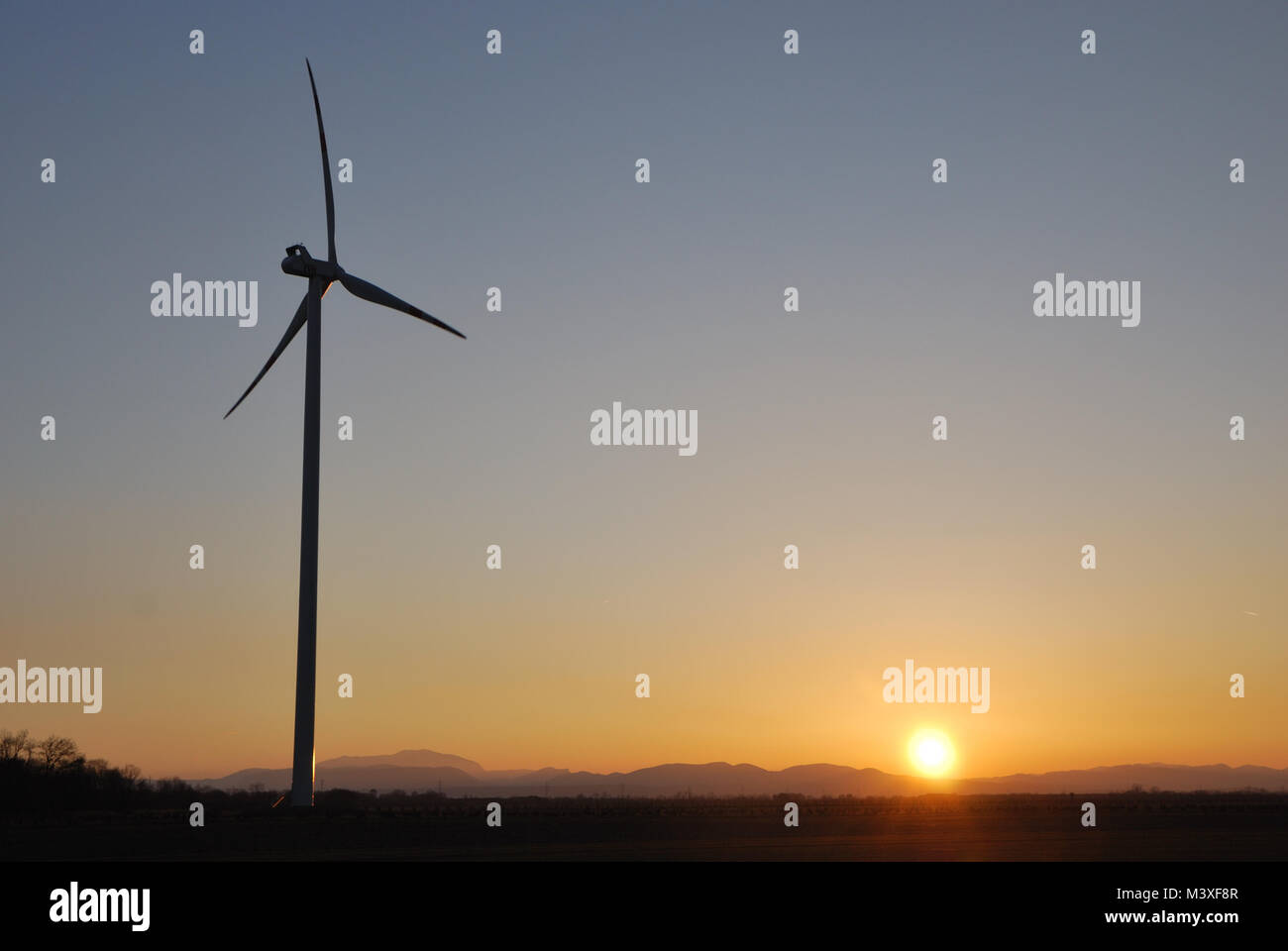 windmill on the left with a lot of mountains in the warm sunset Stock ...
