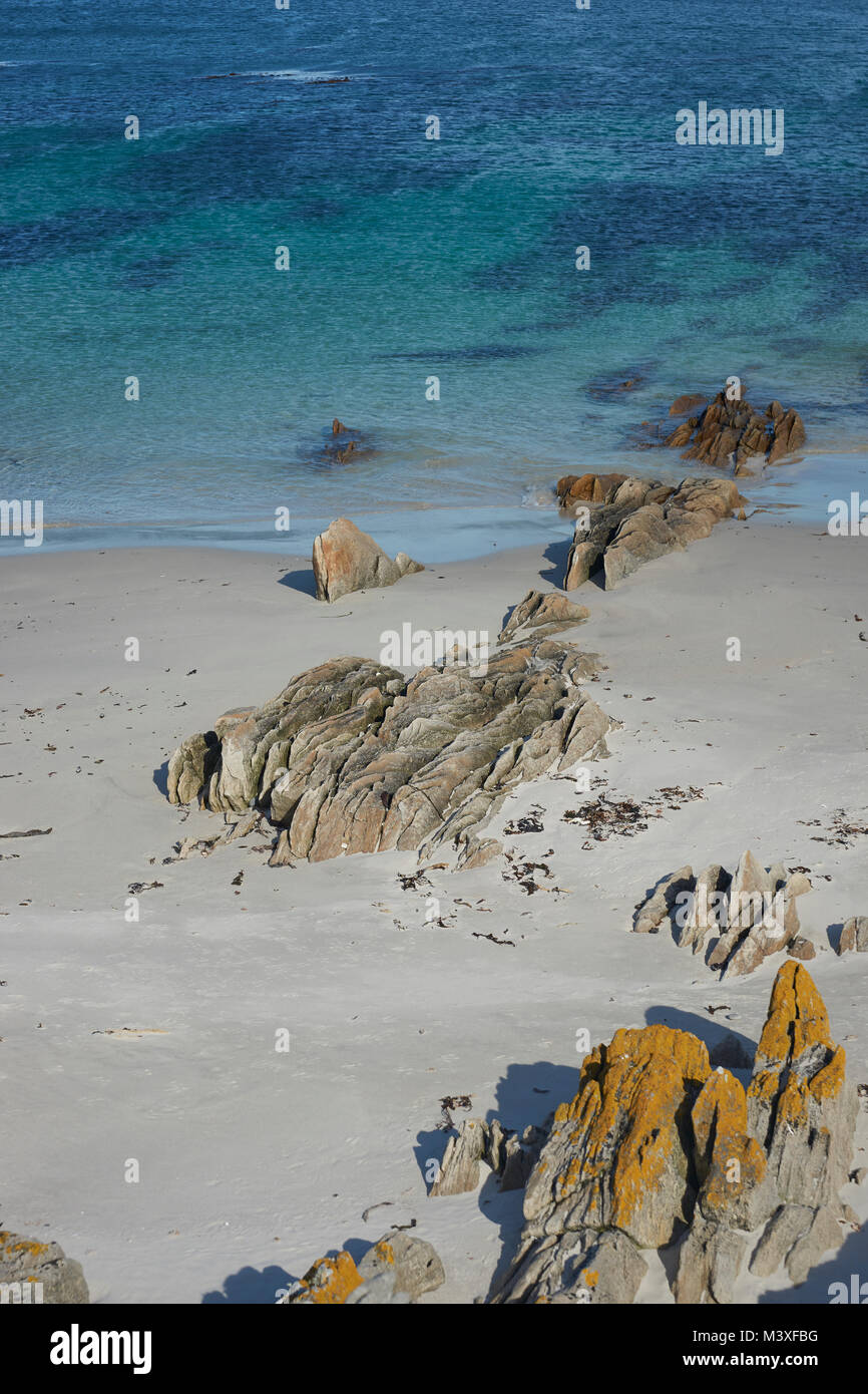 White sandy beach with outcrops of lichen covered rocks on Carcass ...