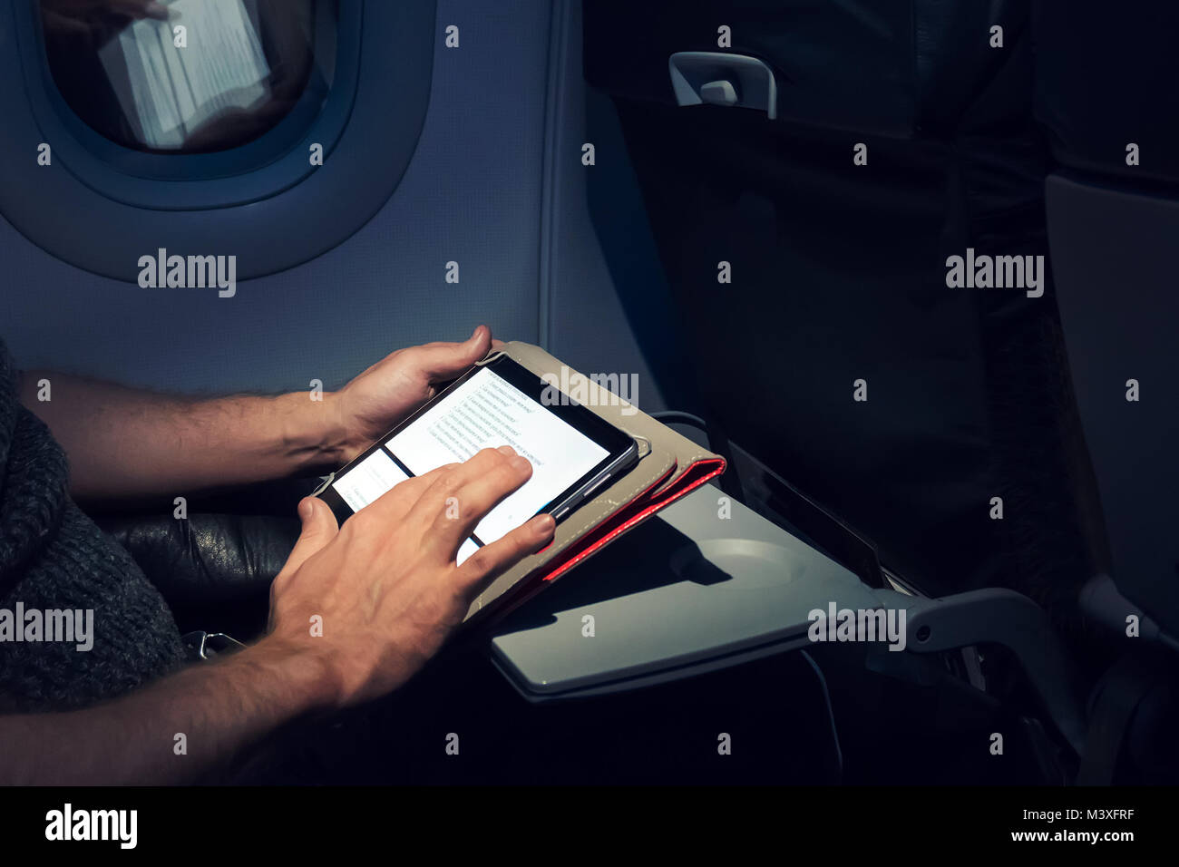 Young man using his tablet on a plane during a flight. This guy's ...