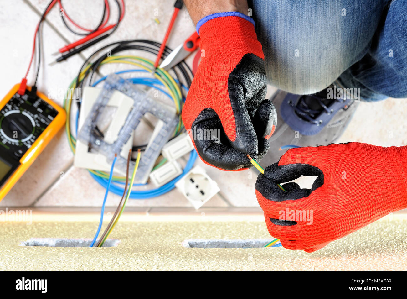 Electrician technician at work prepares the cable with hands protected ...