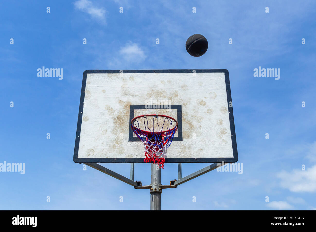 Basketball ball flight against board and net against sky outdoor court ...
