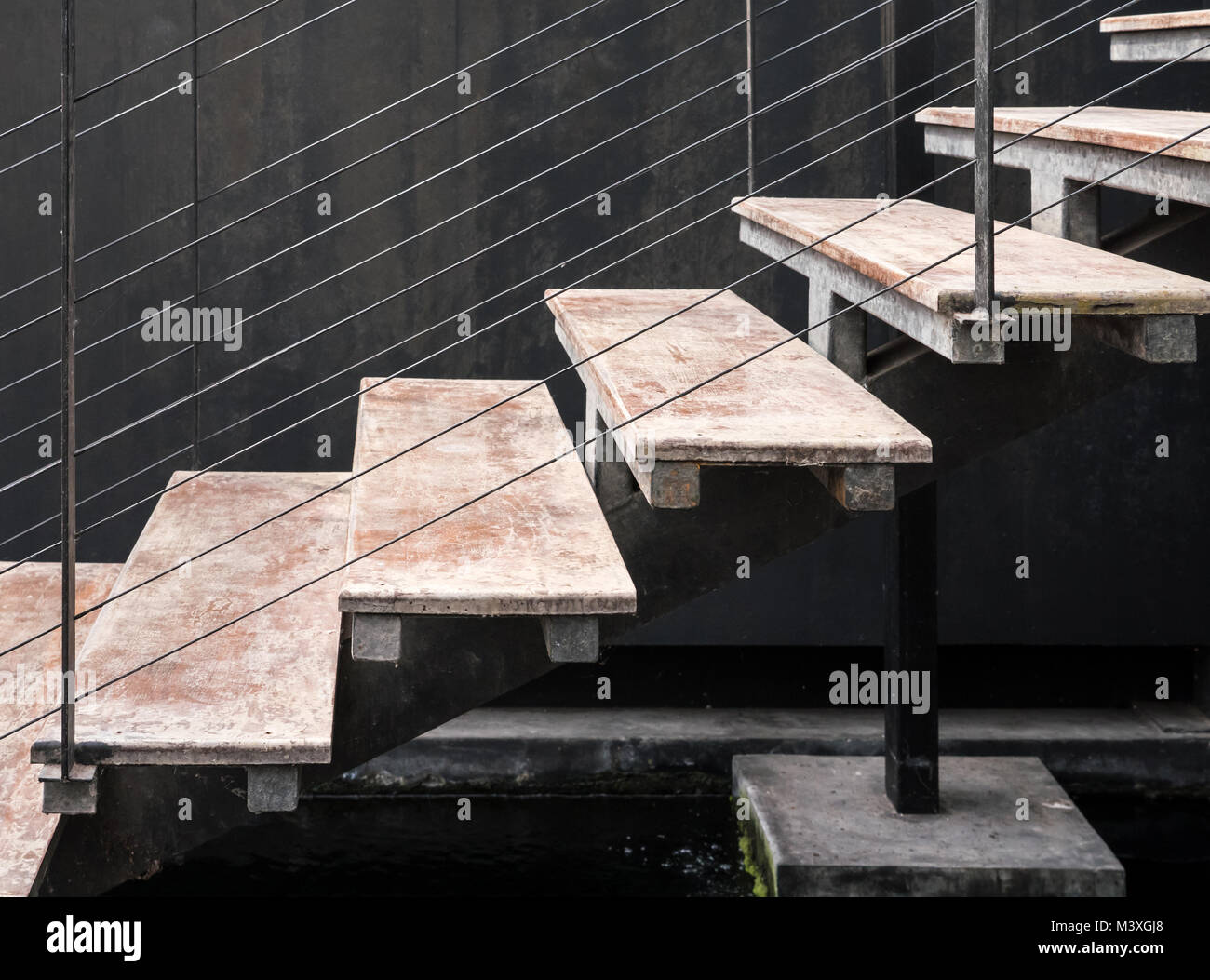 Modern staircase with the metal wire leader over the small pond in the ...