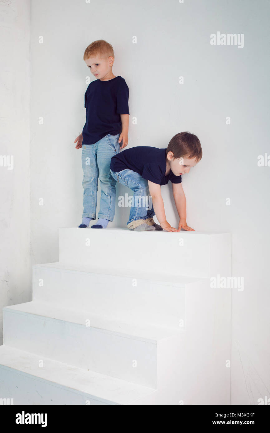 Two boys climb up the stairs. Senior and the younger brother. The ...