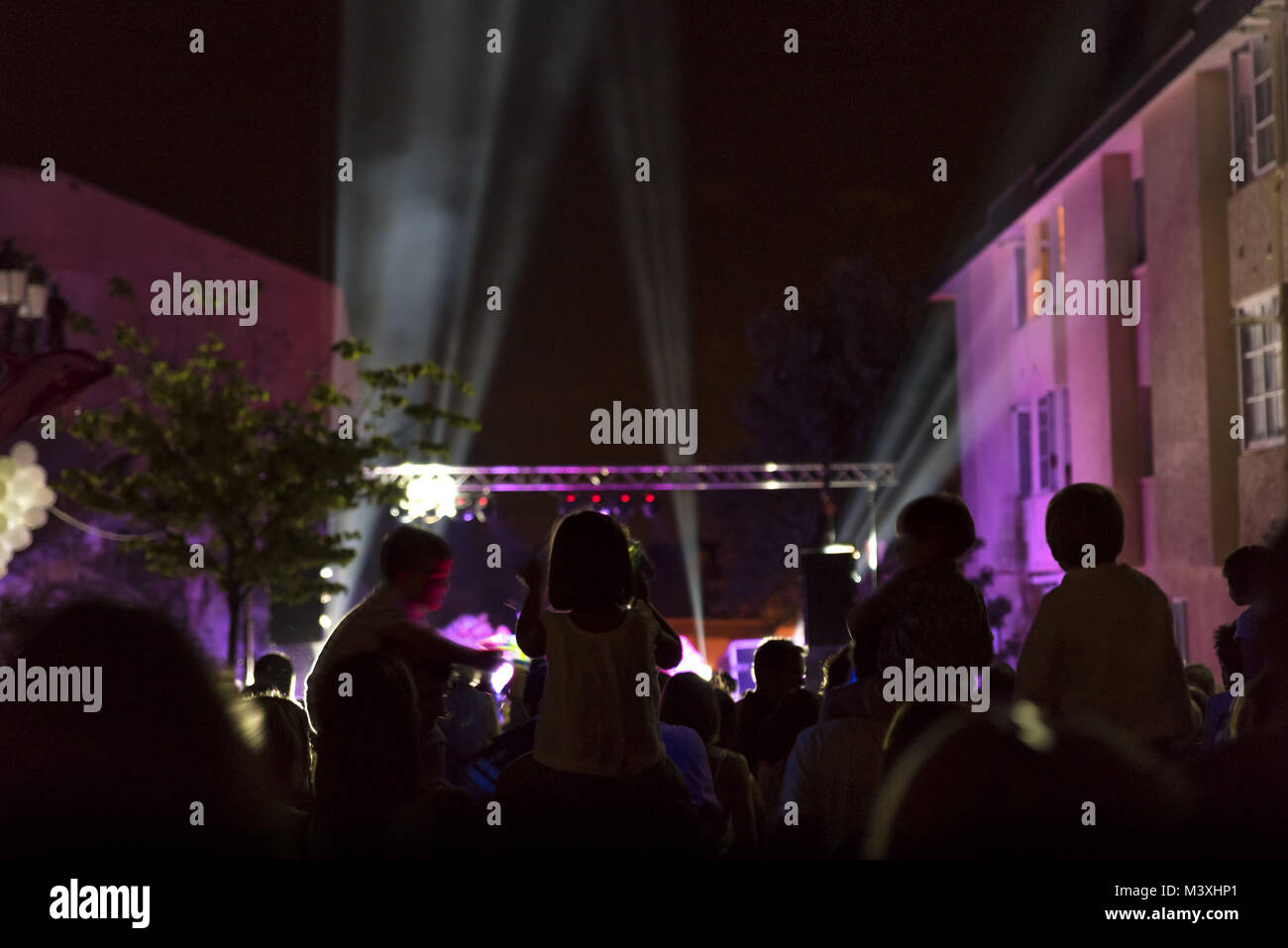 Children sitting on their parents' shoulders watching a concert in the ...